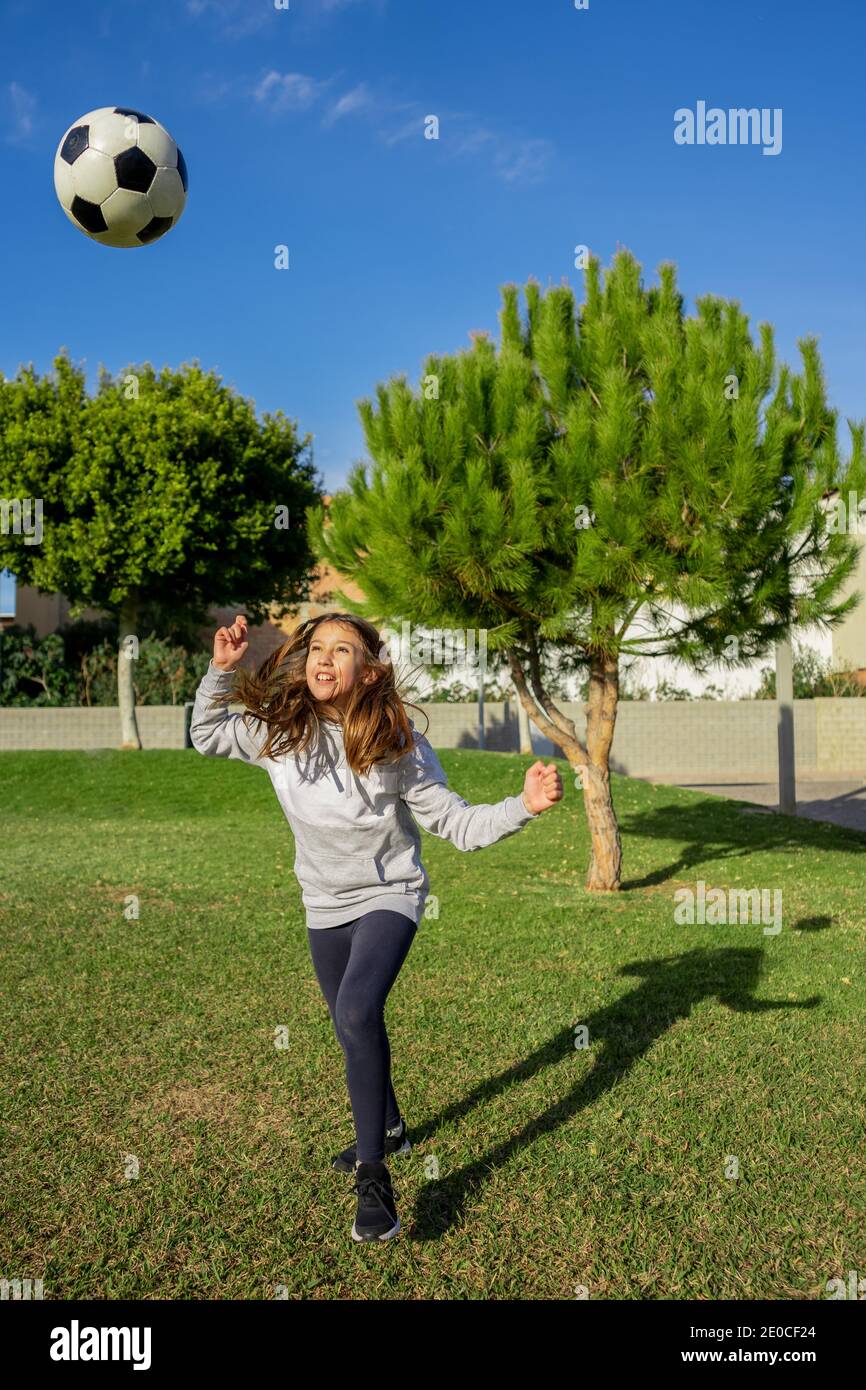 Beautiful little girl playing soccer in a nice park with natural grass ...