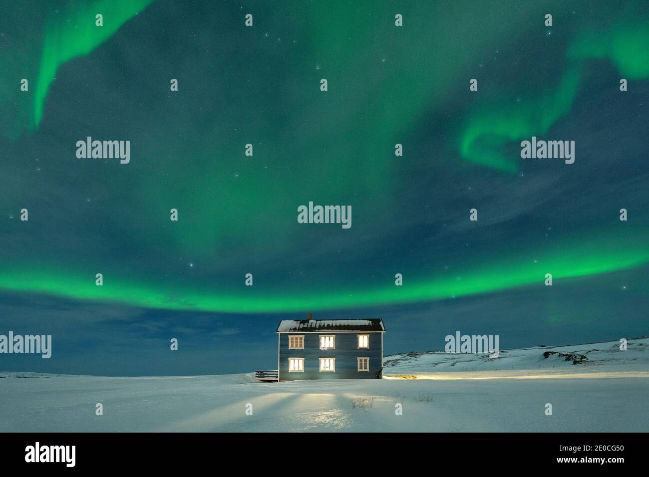 Northern Lights (Aurora borealis) on the illuminated house in the snow ...