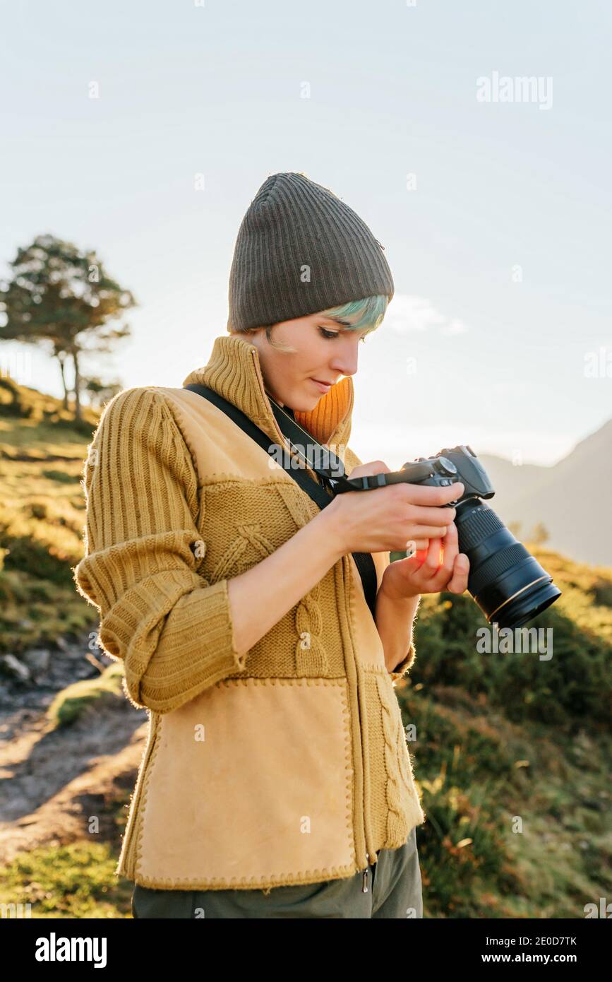 Side view of female photographer taking picture of scenic view of ...
