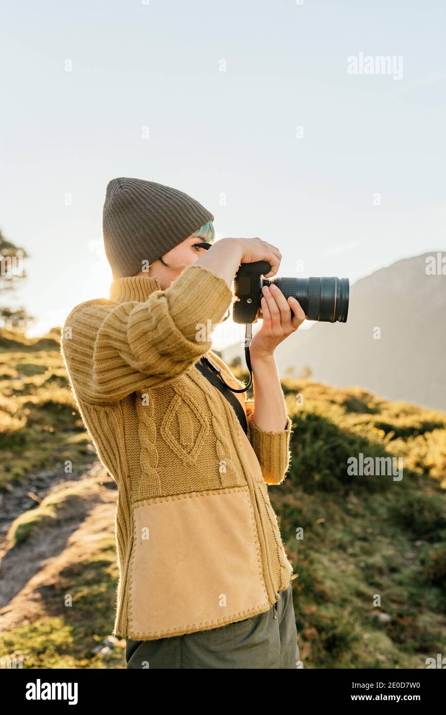 Side view of female photographer taking picture of scenic view of ...