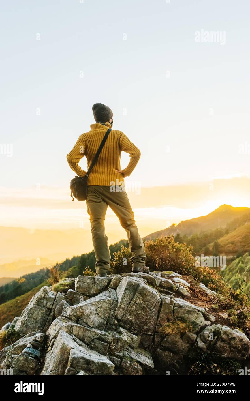Back view of unrecognizable explorer standing on rough rock and ...