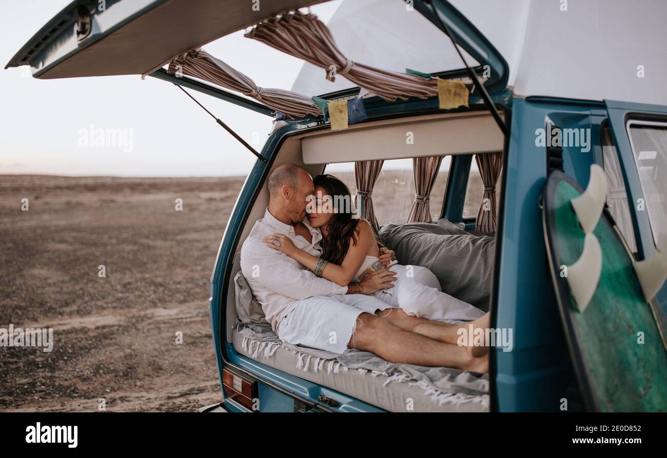 Gentle couple of travelers relaxing in van and tenderly hugging while ...