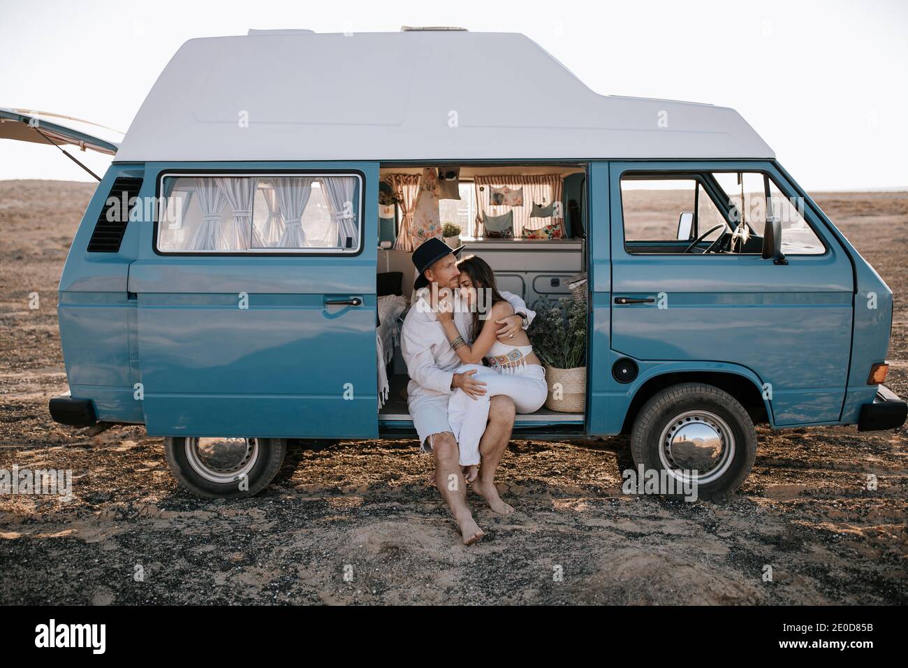 Loving couple of travelers sitting in parked van and hugging while ...