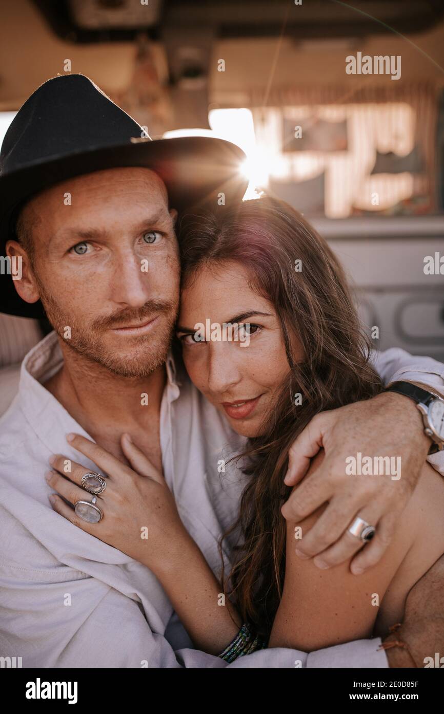 Loving couple of travelers sitting in parked van and hugging while ...