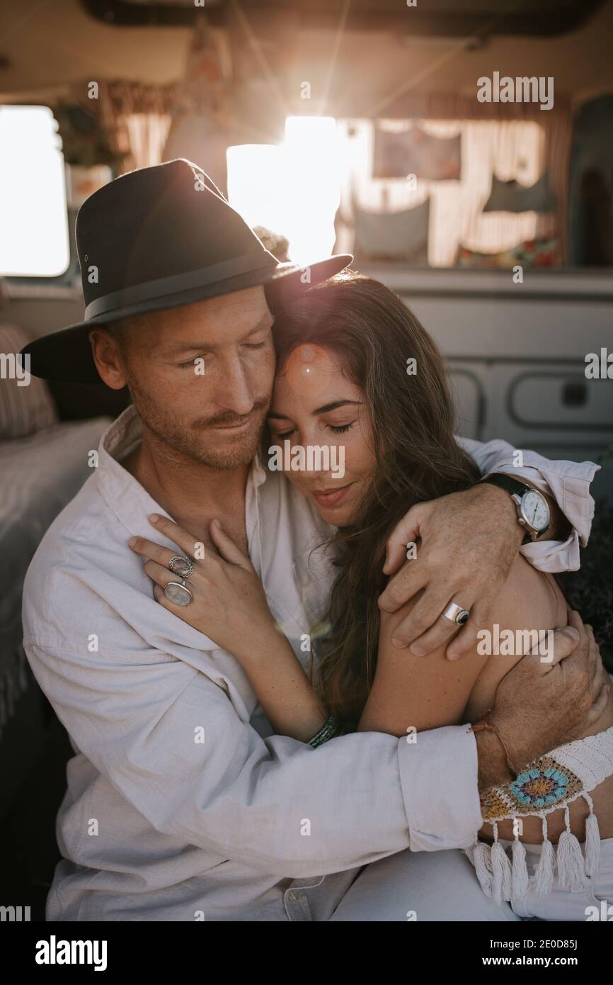 Loving couple of travelers sitting in parked van and hugging while ...