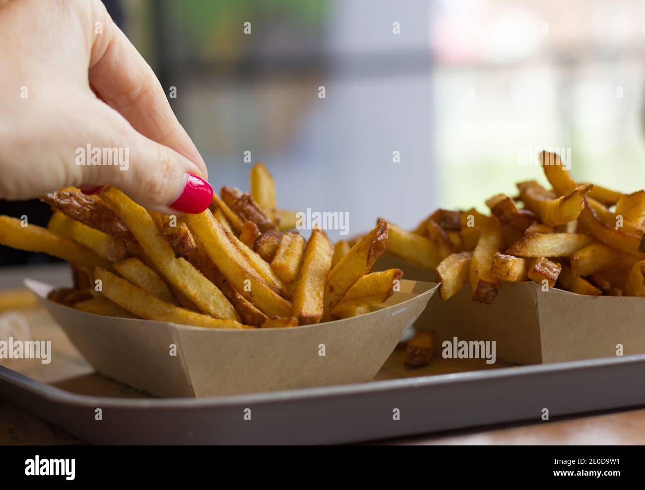 Hand of woman with pink painted nails grabbing french fries in fast ...