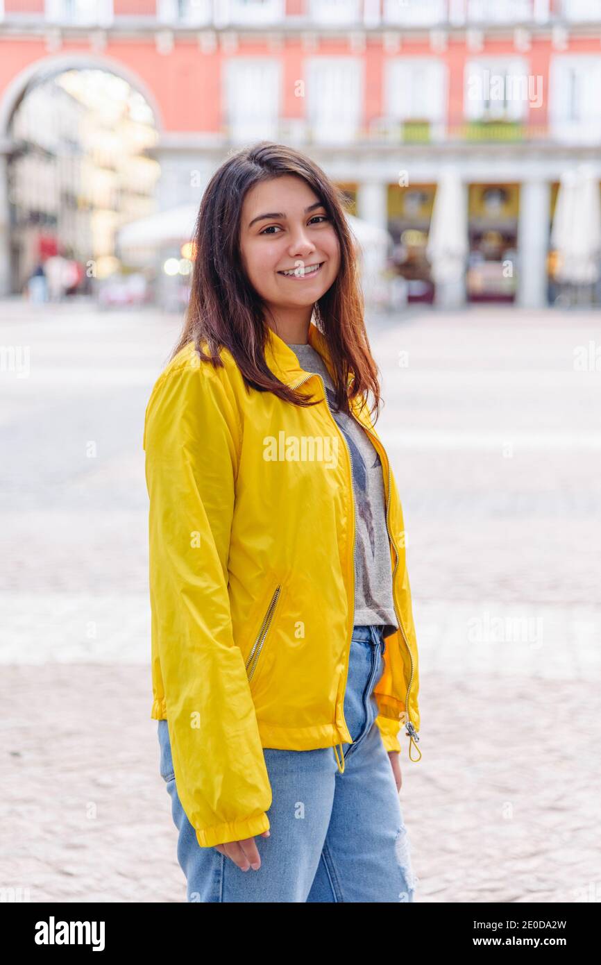 Side view of young charming female in casual bright outfit standing in ...