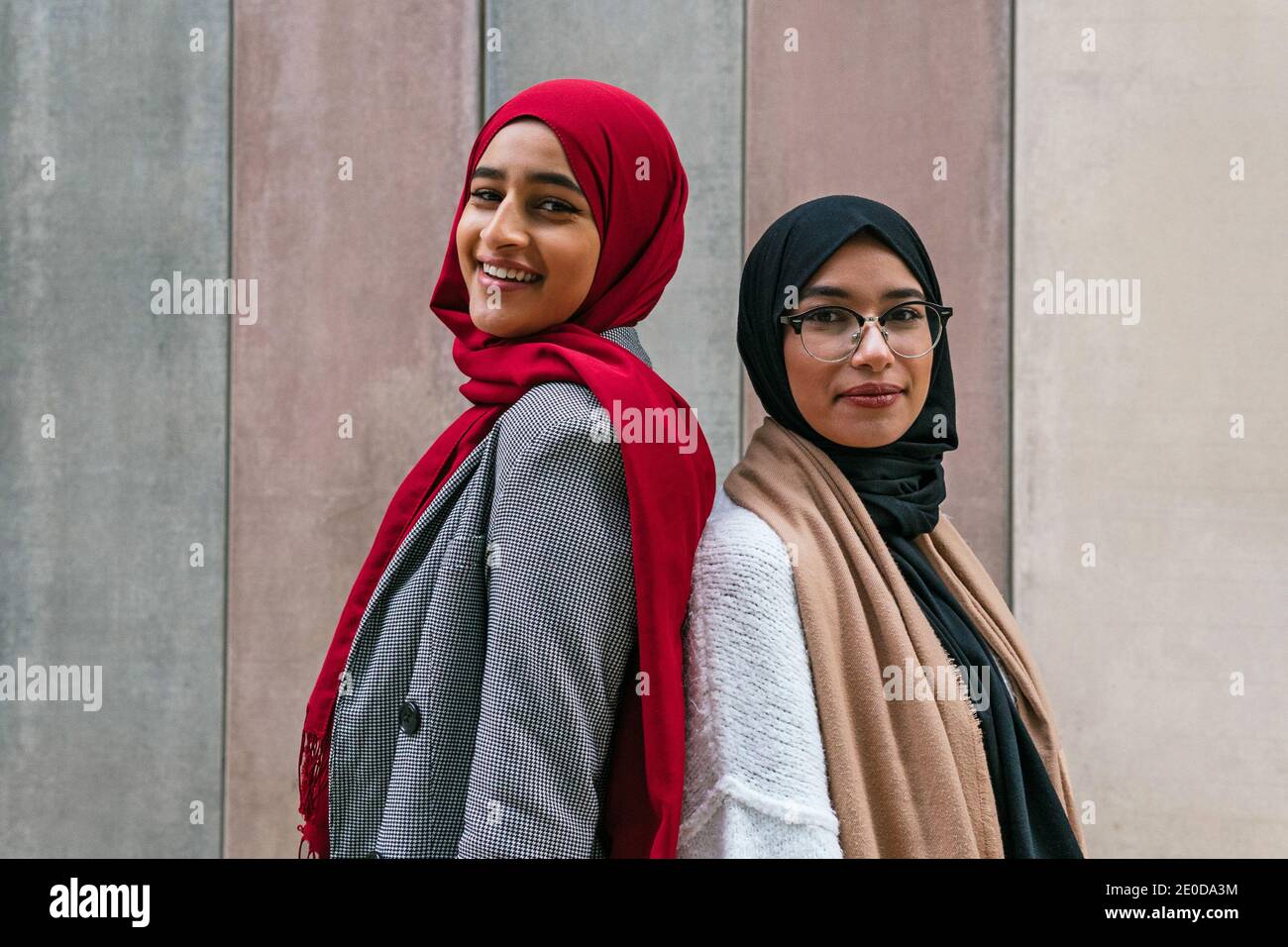 Side view of Arab female friends in traditional hijab standing back to ...