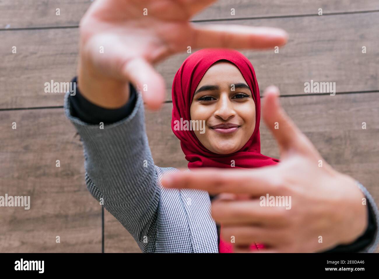 Low angle of cheerful Arab female in hijab looking at camera and making ...