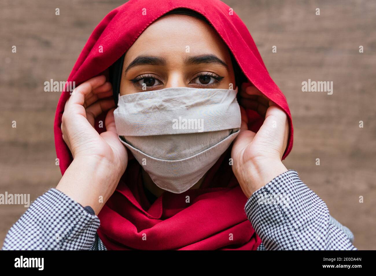 Calm Arab female in hijab standing in street and putting on protective ...