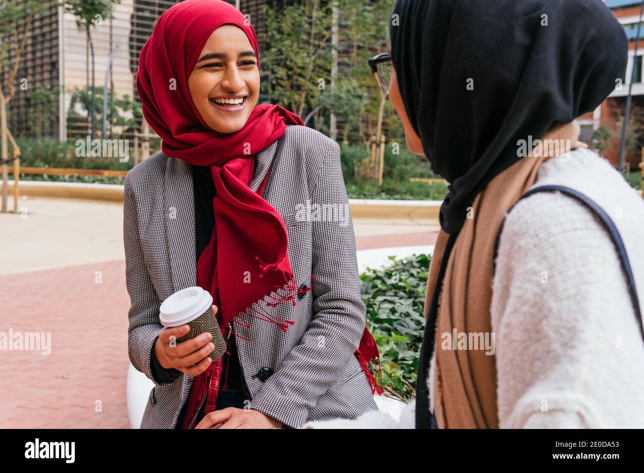 Friendly Arab female friends sitting on street and talking to each ...