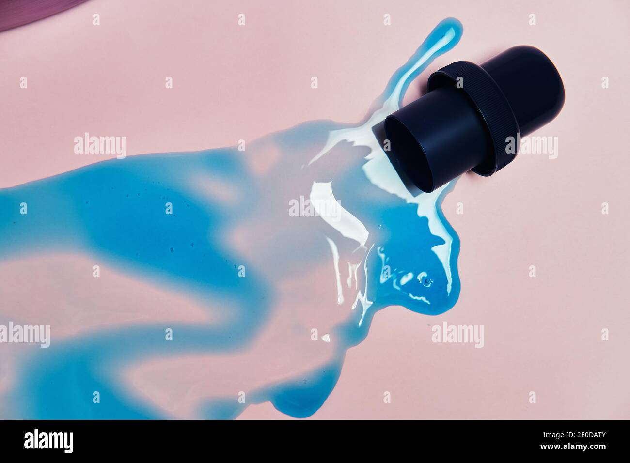 Top view of liquid detergent spilled from plastic cap on pink ...