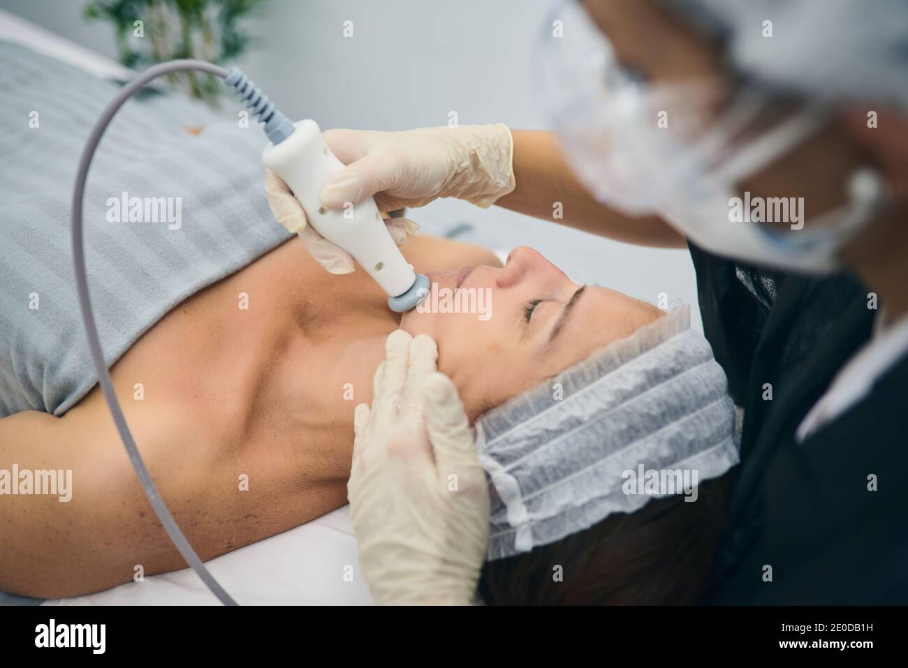 Professional dermatologist applying RF lifting machine on face of ...