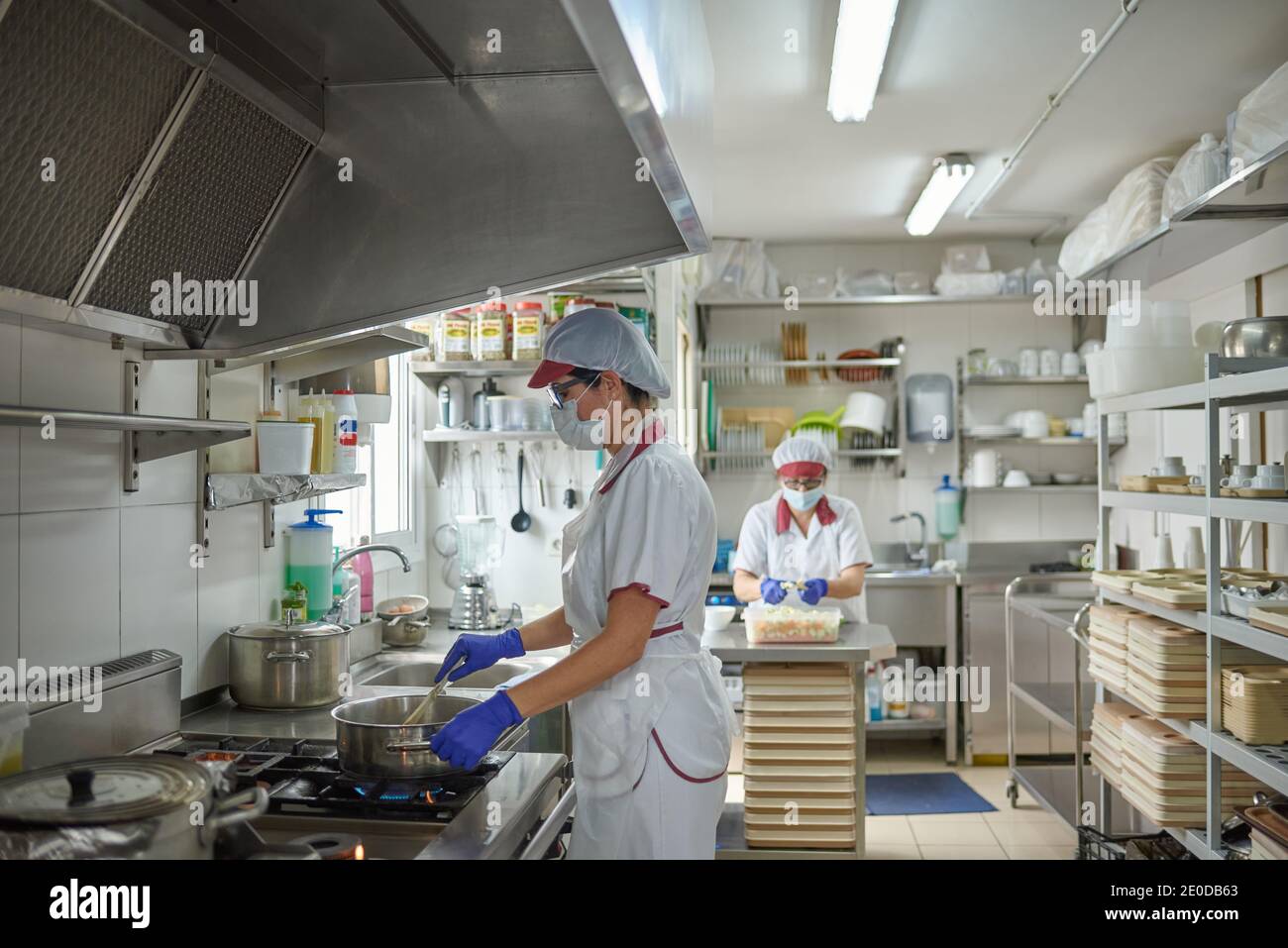 Professional female cook in white uniform and protective mask and ...