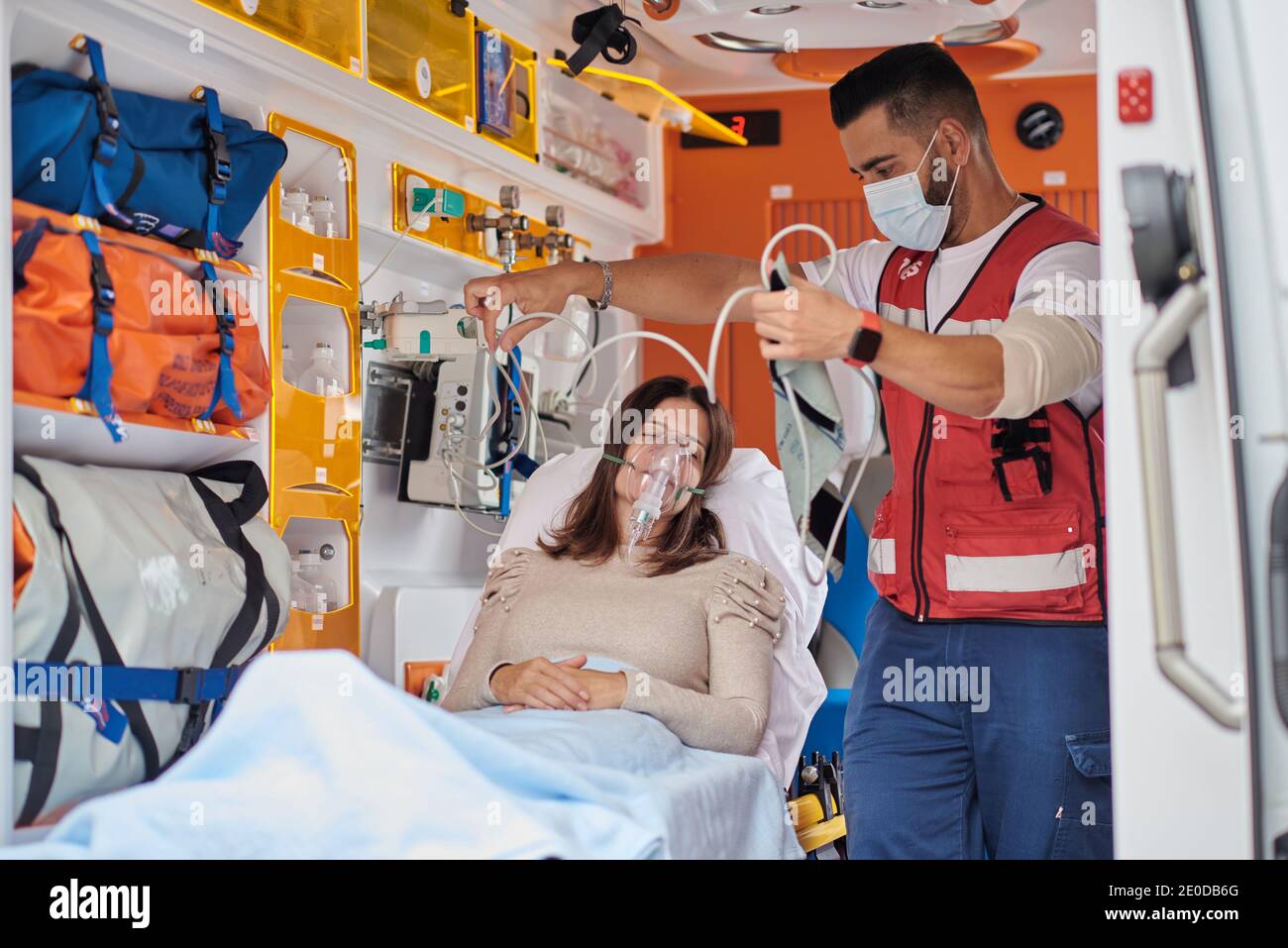 Paramedic putting ventilator mask to patient lying on medical stretcher ...