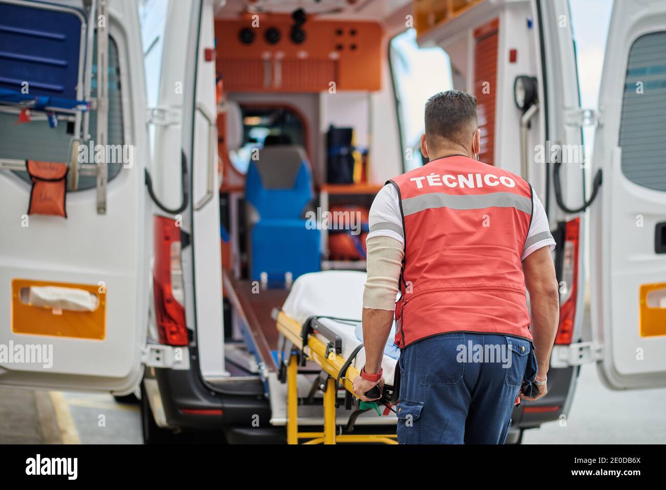 Back view of professional male paramedic in protective mask pulling ...