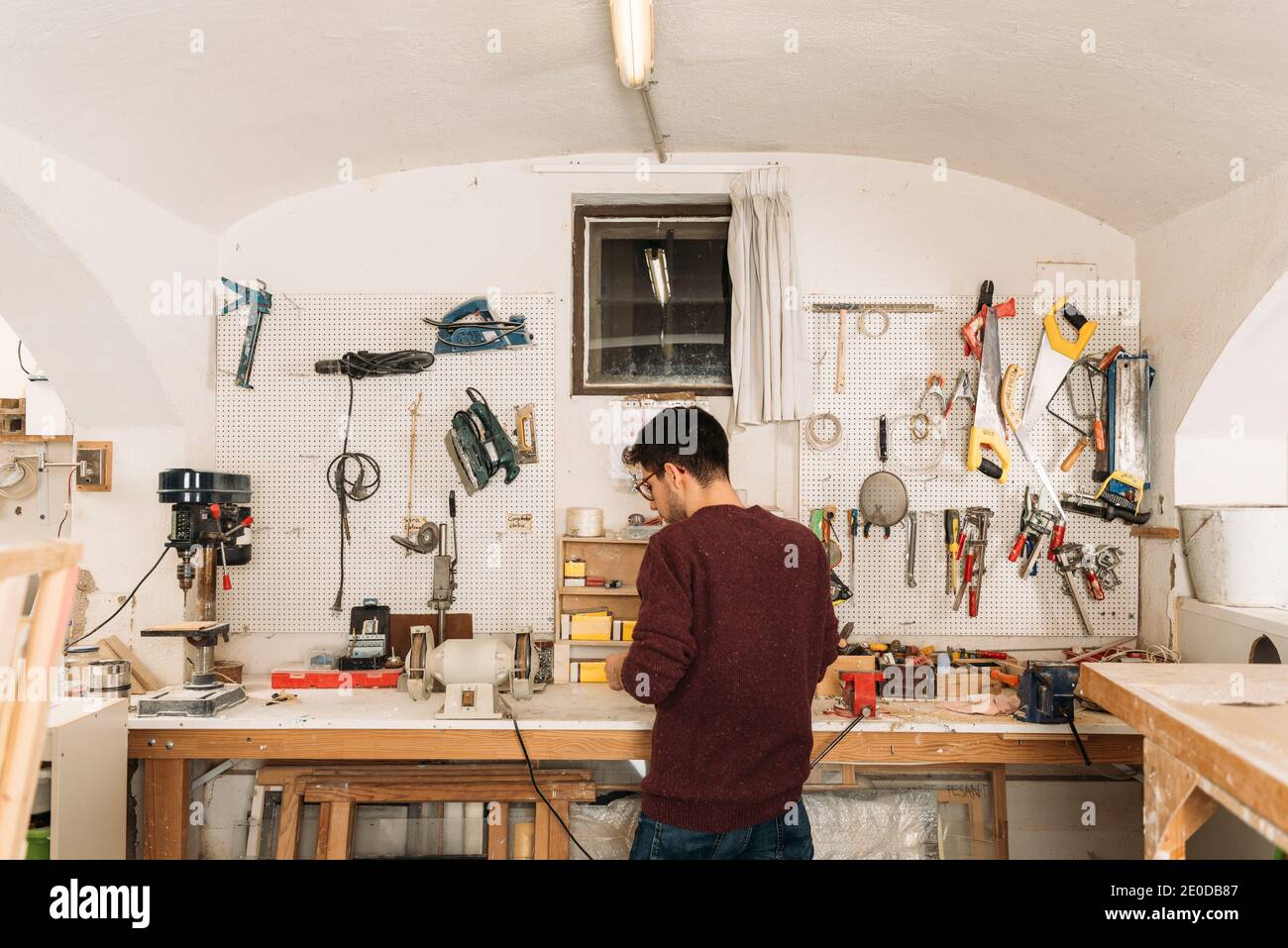 Back view of male woodworker standing at workbench and creating wooden ...