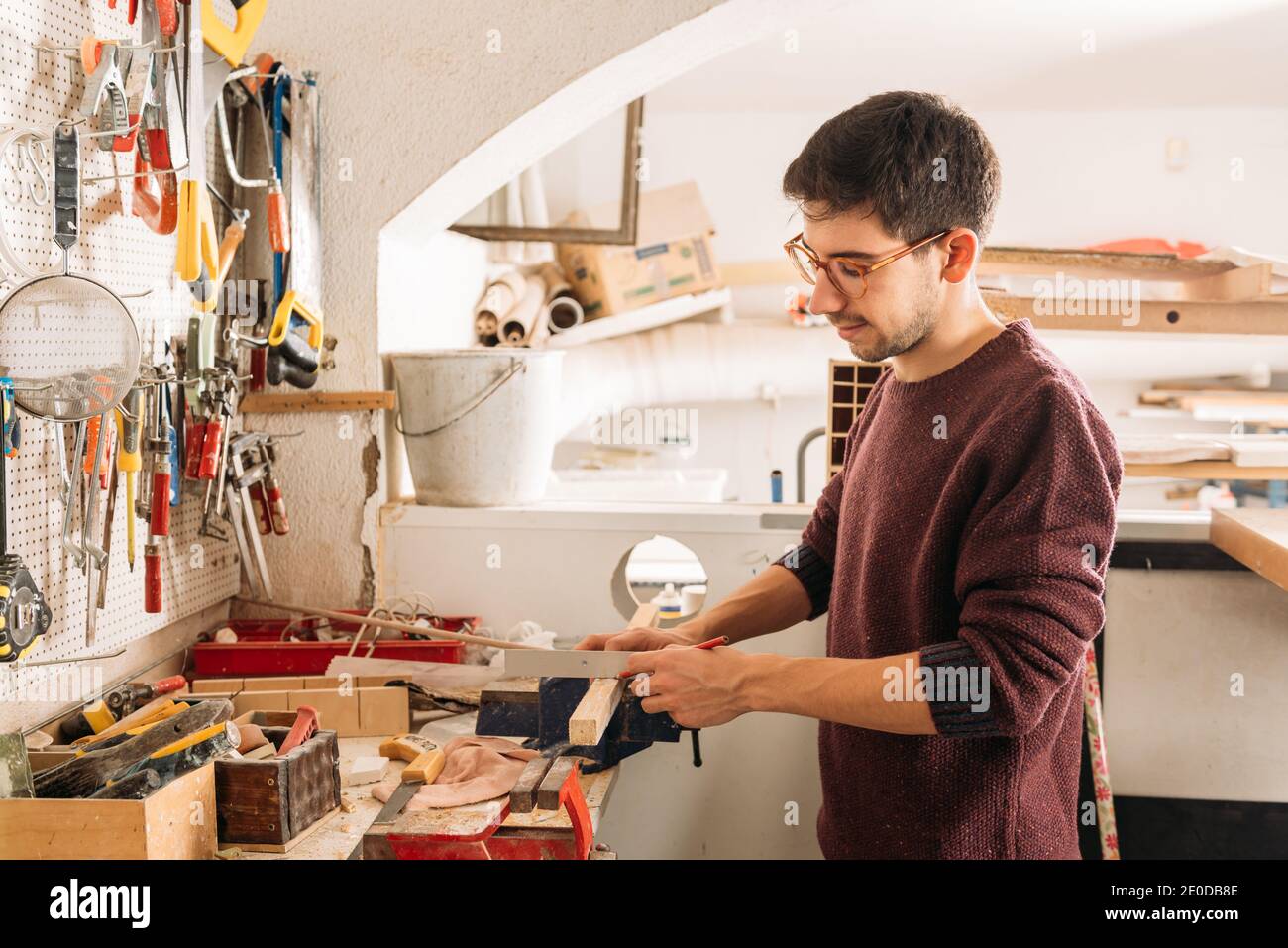 Side view of crop faceless male carpenter using metal angle and wooden ...