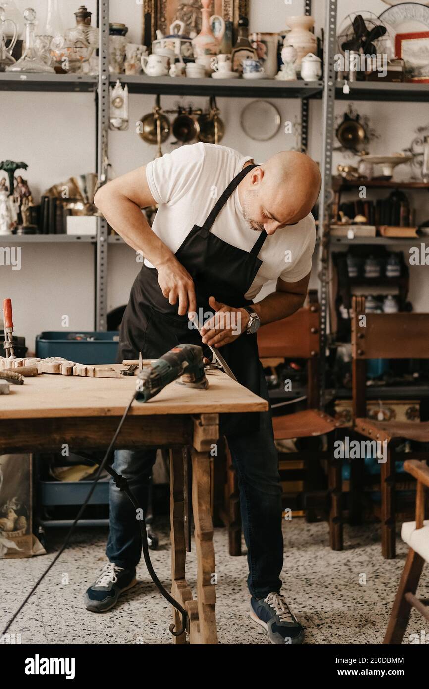 Focused middle aged carpenter using hammer and chisel while making ...