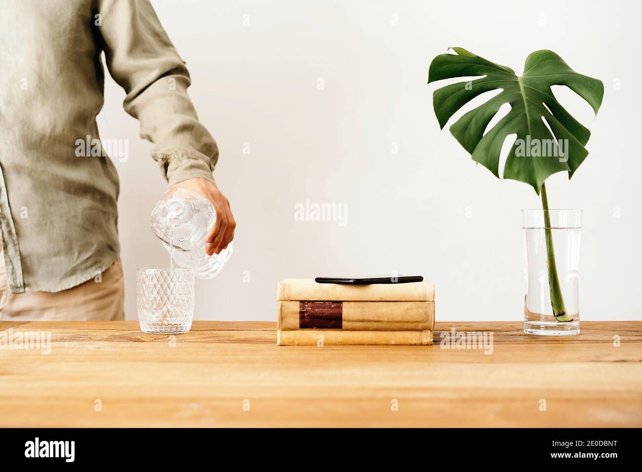 Crop anonymous male filling glass with fresh mineral water from plastic ...