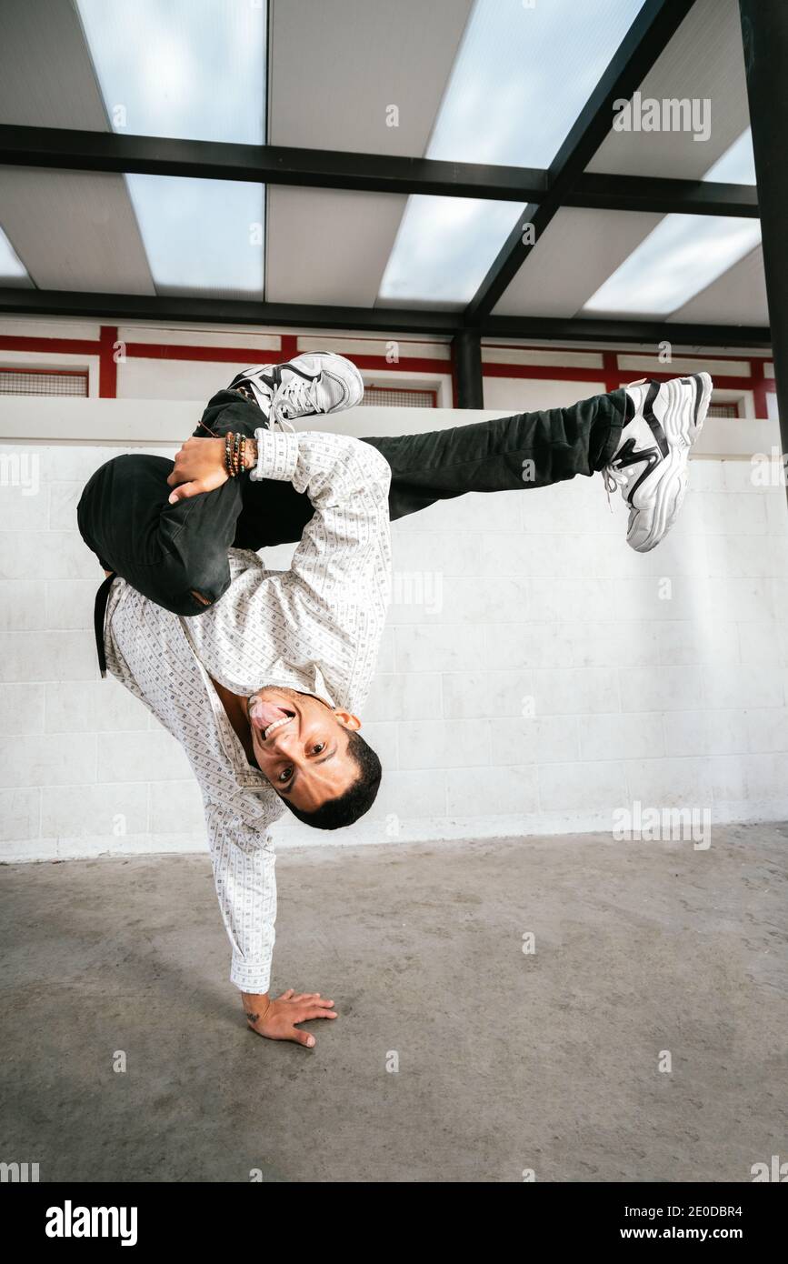 Full body of energetic young man doing acrobatic handstand while ...