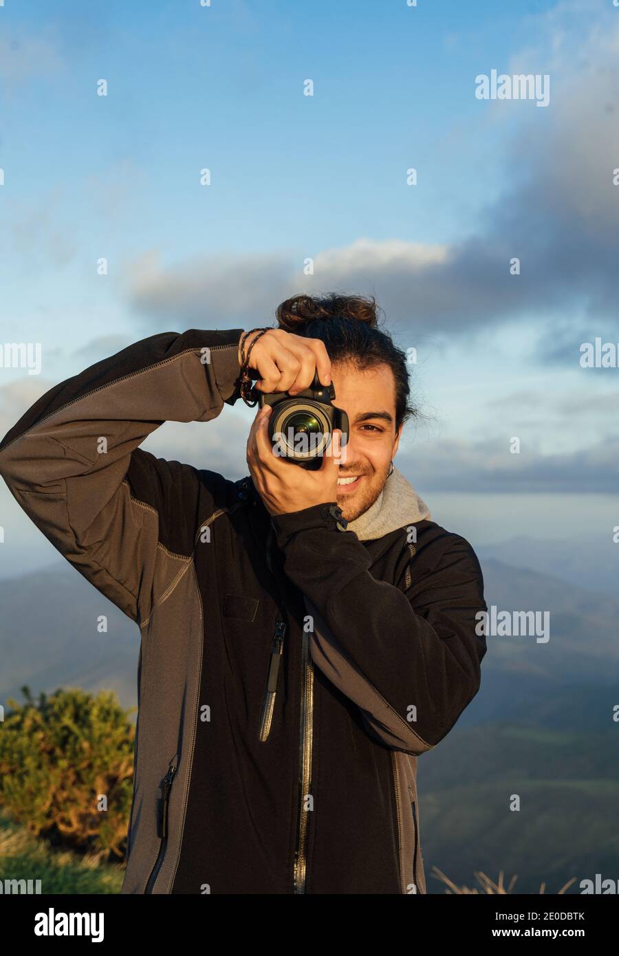 Young male photographer with professional photo camera taking pictures ...