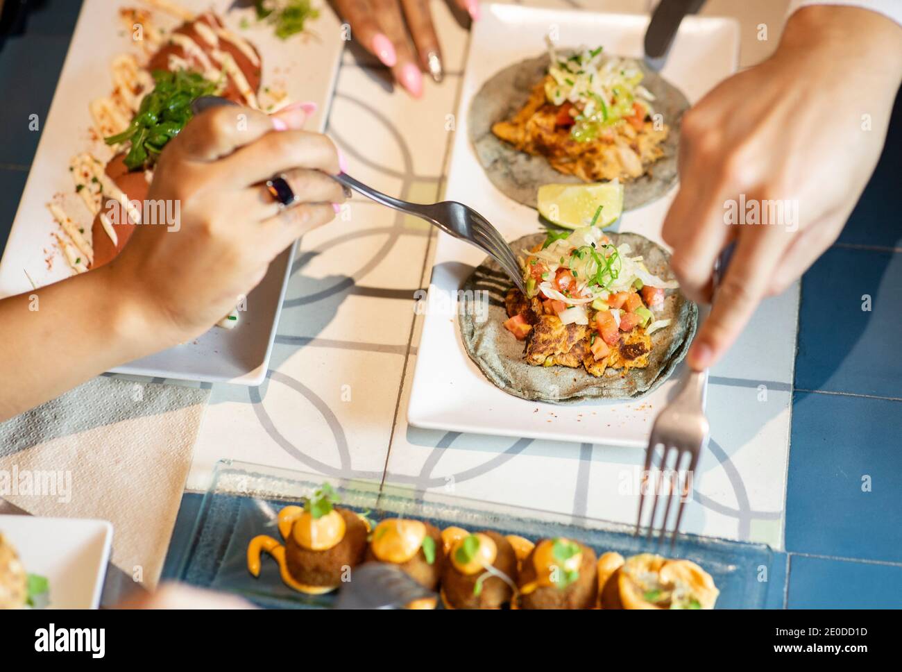 Group of crop anonymous friends gathering at table with various snacks ...