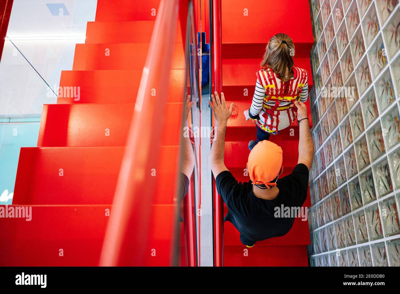 From above of little girl with disability walking up steps with support ...