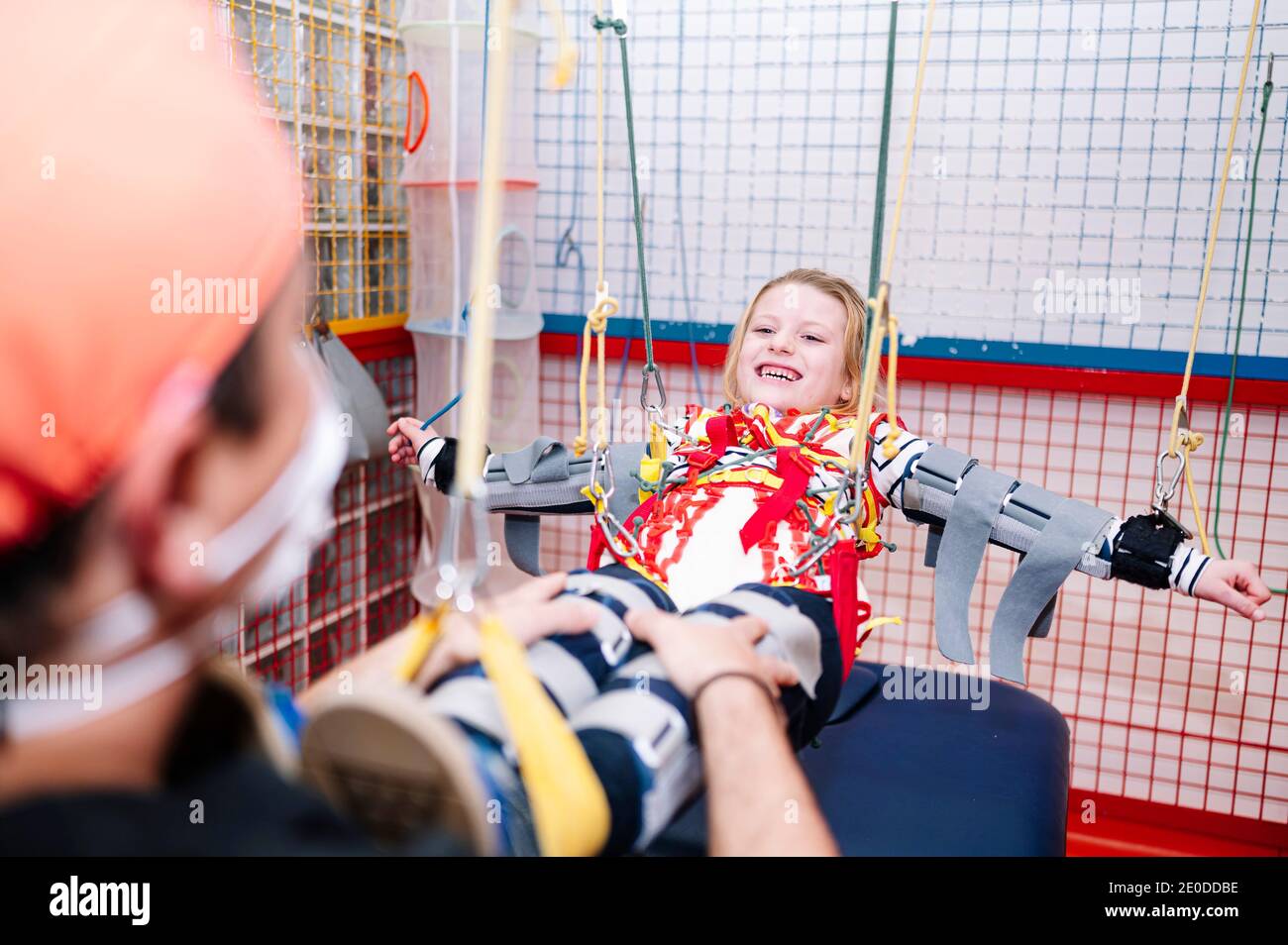 Crop anonymous specialist giving support to girl with Angelman syndrome ...