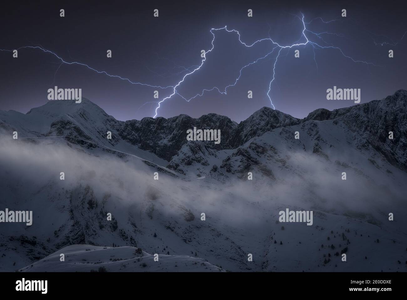 Scenery of mountain range covered with snow under thunderstorm sky with ...