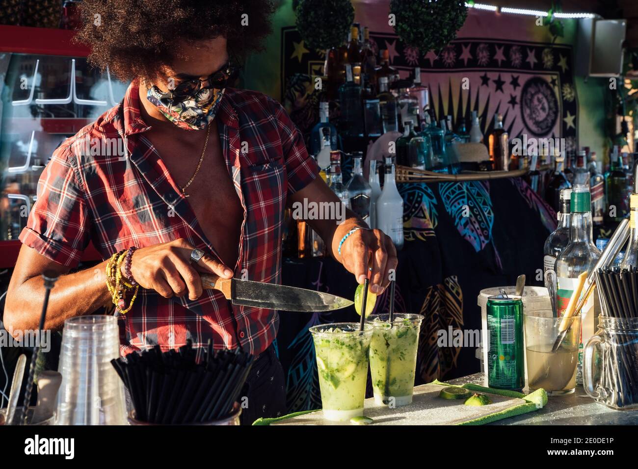 African American male barkeeper in protective mask garnishing cocktail ...