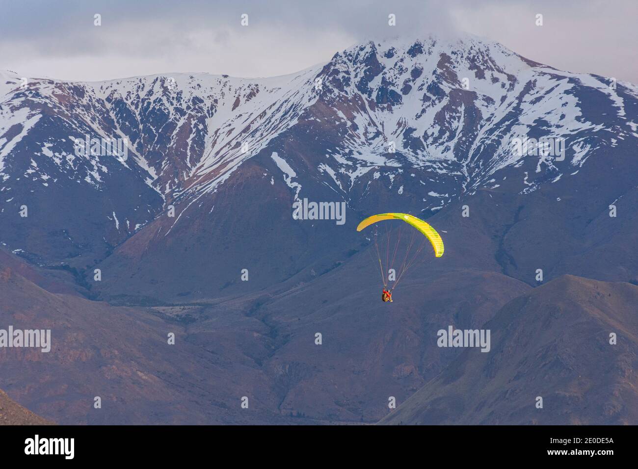 Paragliding against snow-capped Andes mountains during winter season in ...