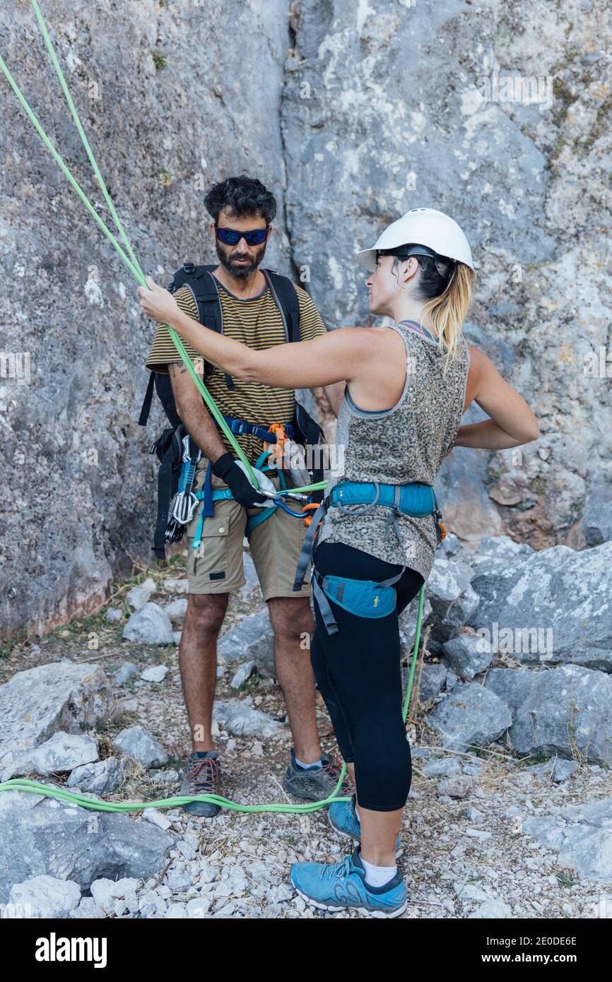 Fearless active couple in safety harnesses preparing gear for ascending ...