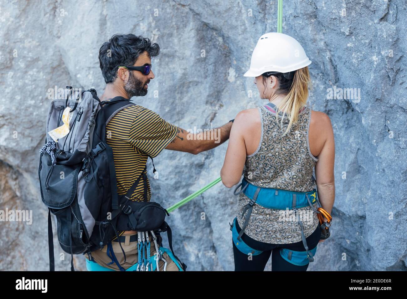 Fearless active couple in safety harnesses preparing gear for ascending ...