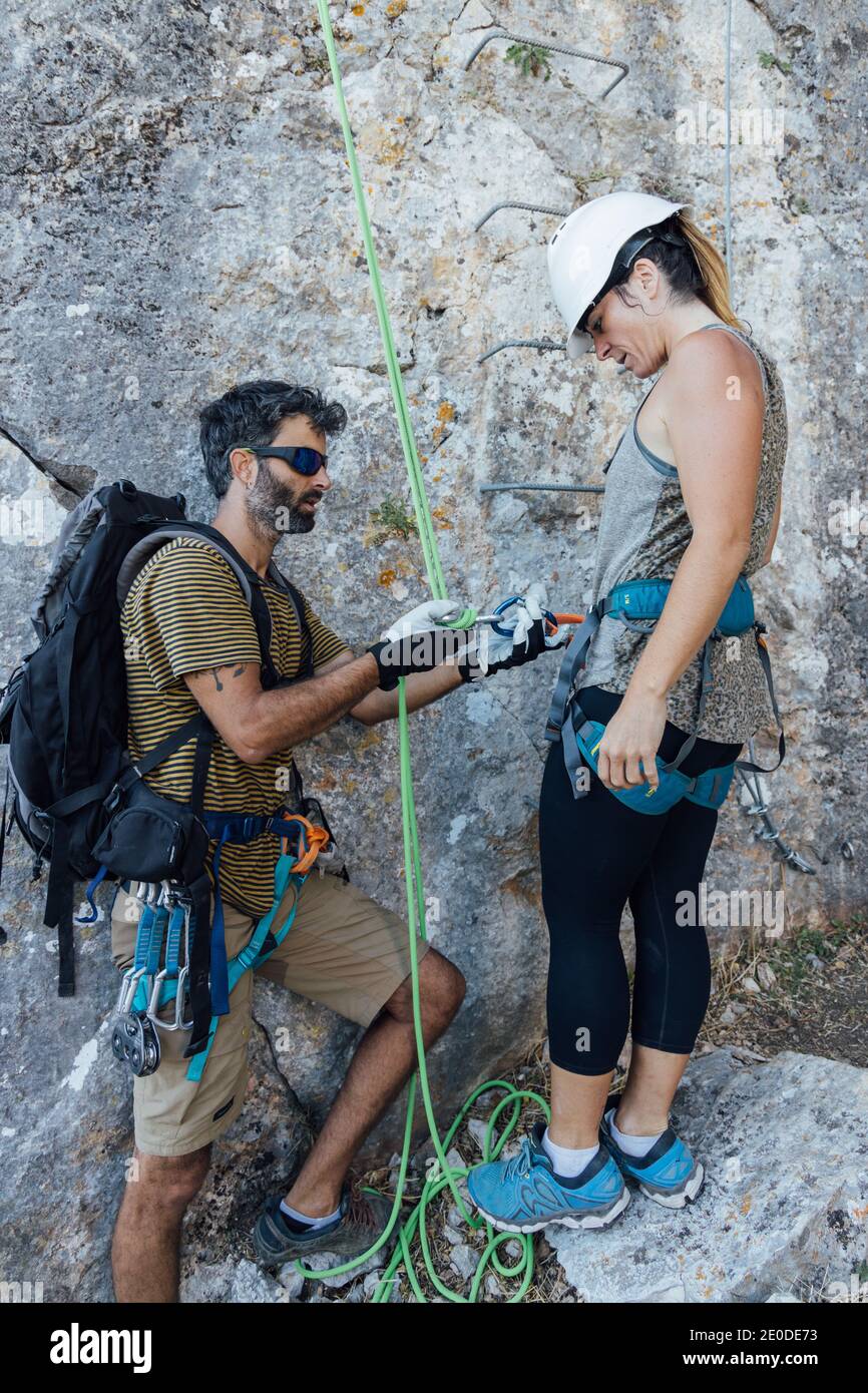 Side view fearless active couple in safety harnesses preparing gear for ...