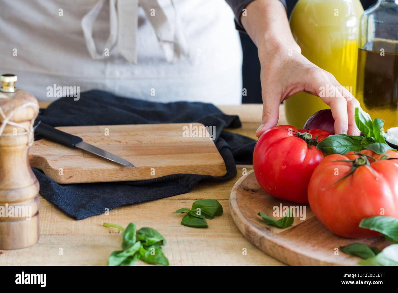 Unrecognizable crop person chopping fresh tomatoes on wooden cutting ...