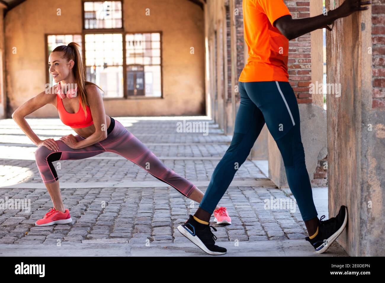 Flexible diverse runners in sportswear doing bends while stretching ...