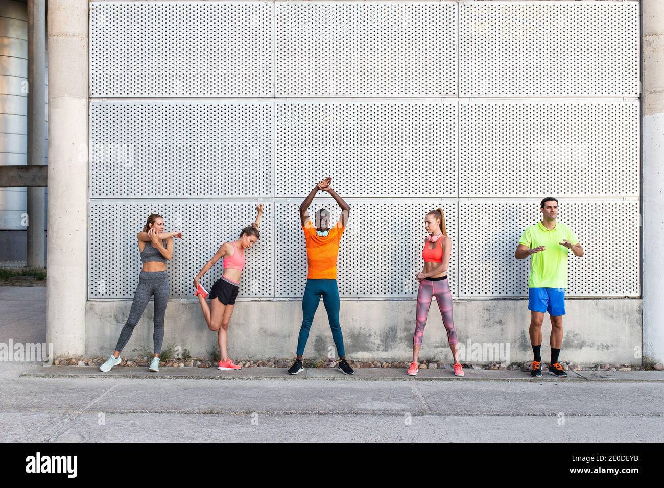 Group of multiracial runners in activewear standing in street and ...