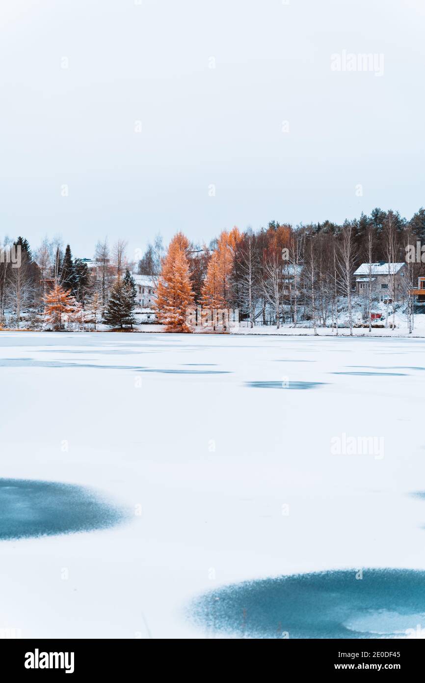 Spectacular scenery of frozen lake near village with residential houses ...