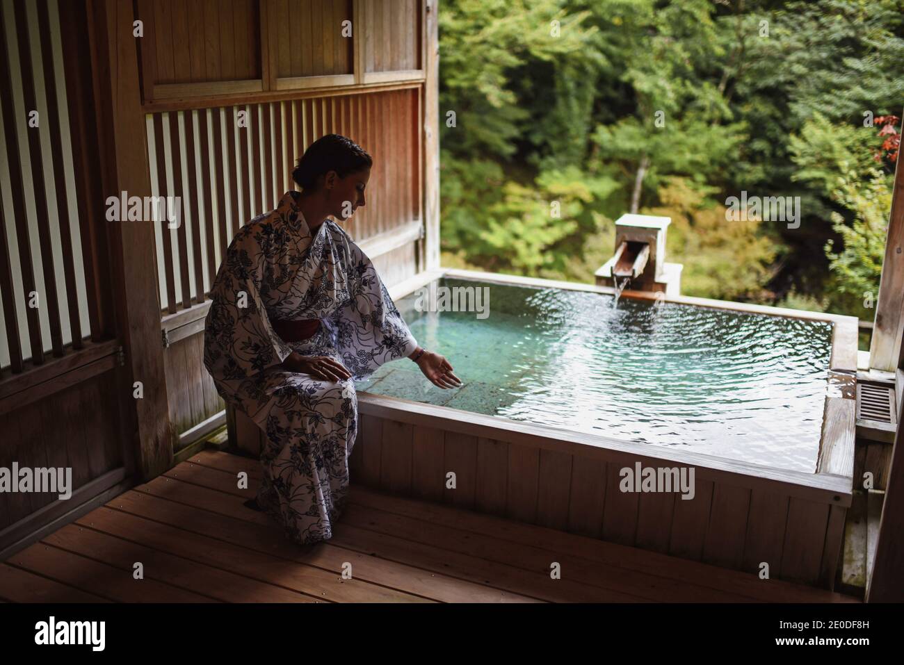 Young caucasian Woman in a kimono touching thermal waters before ...