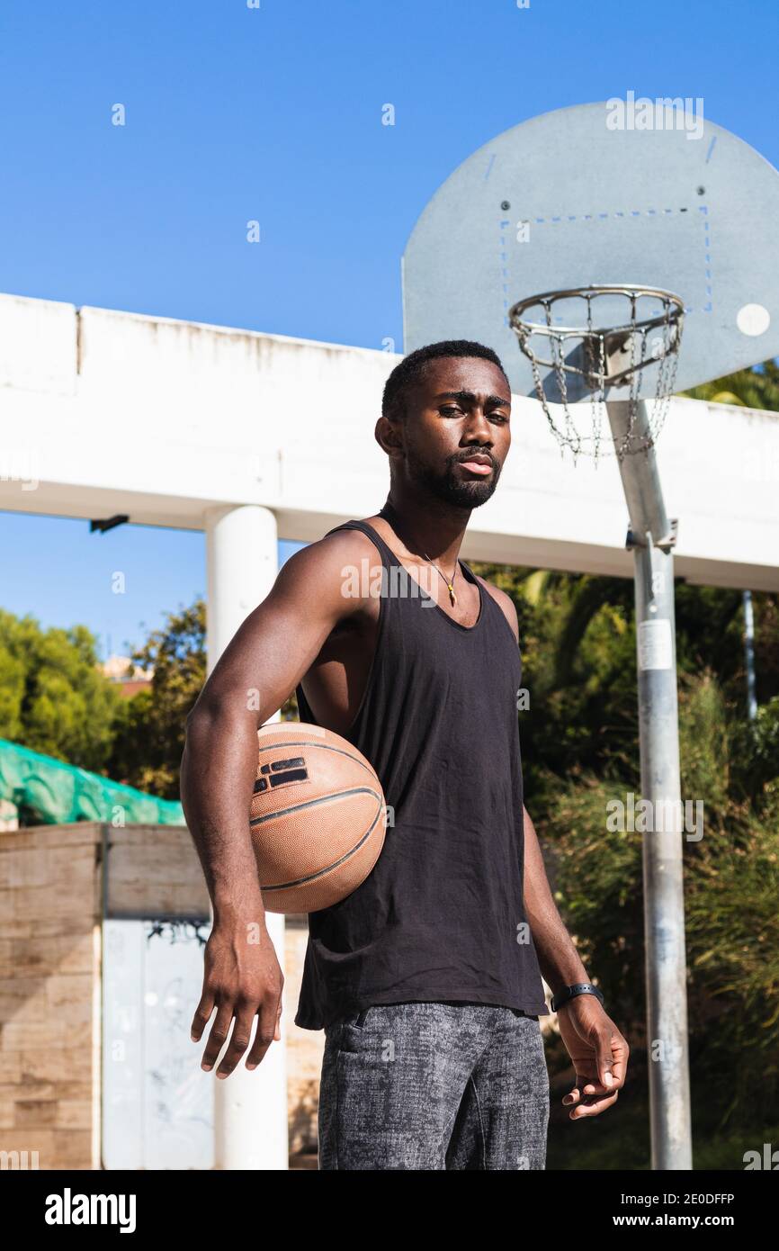 Fit African American male standing on basketball court with ball and ...