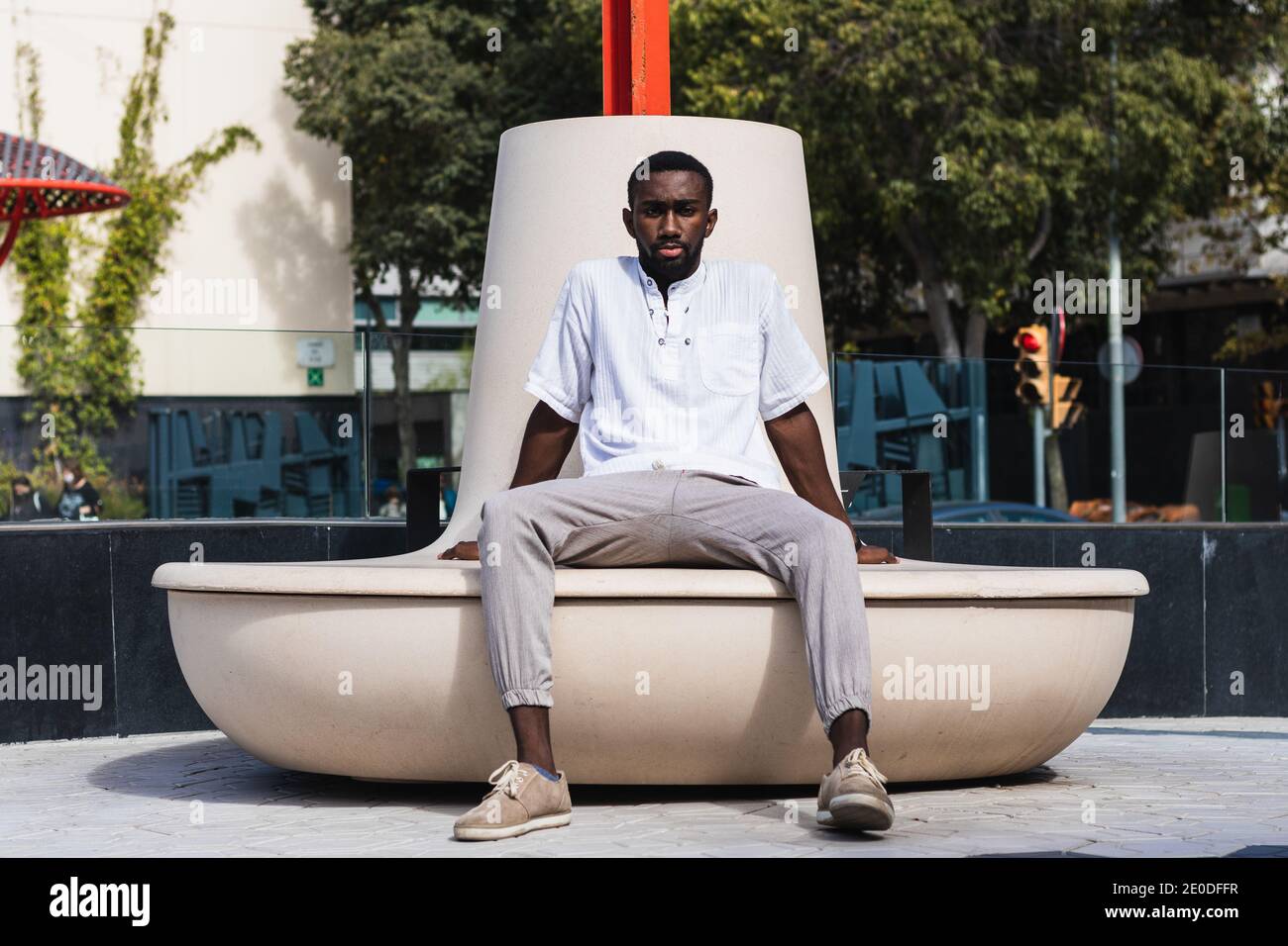 Confident African American male in summer outfit relaxing on concrete ...