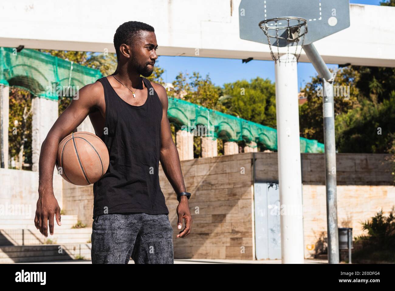 Fit African American male standing on basketball court with ball and ...