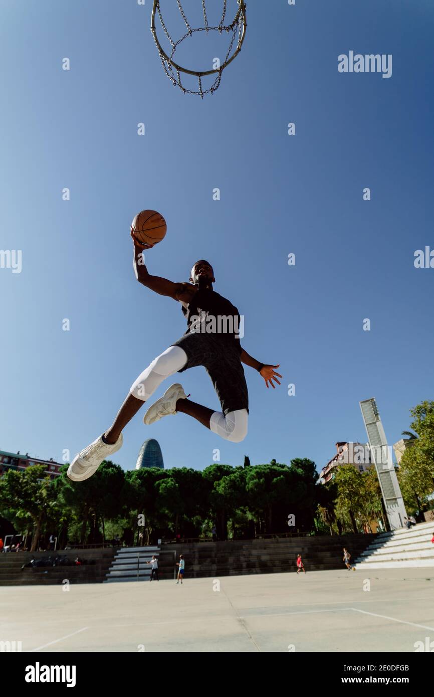 Low angle of fit black male basketball player in moment of jumping ...