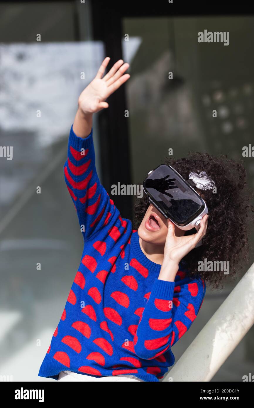 Excited female wearing modern VR glasses experiencing virtual reality ...