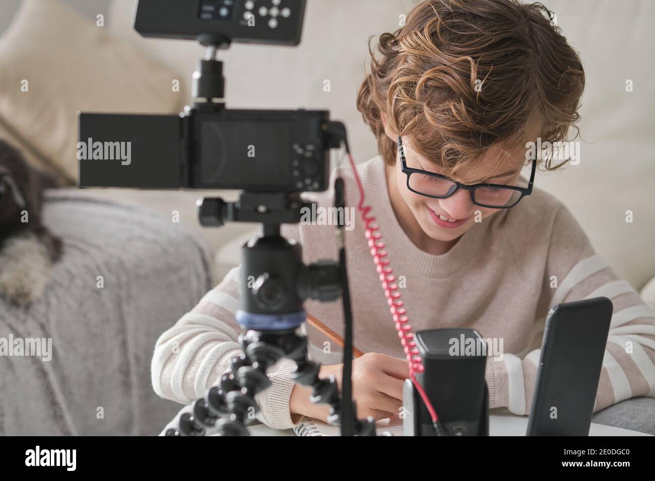Cheerful youtuber boy taking notes and preparing video for his channel ...