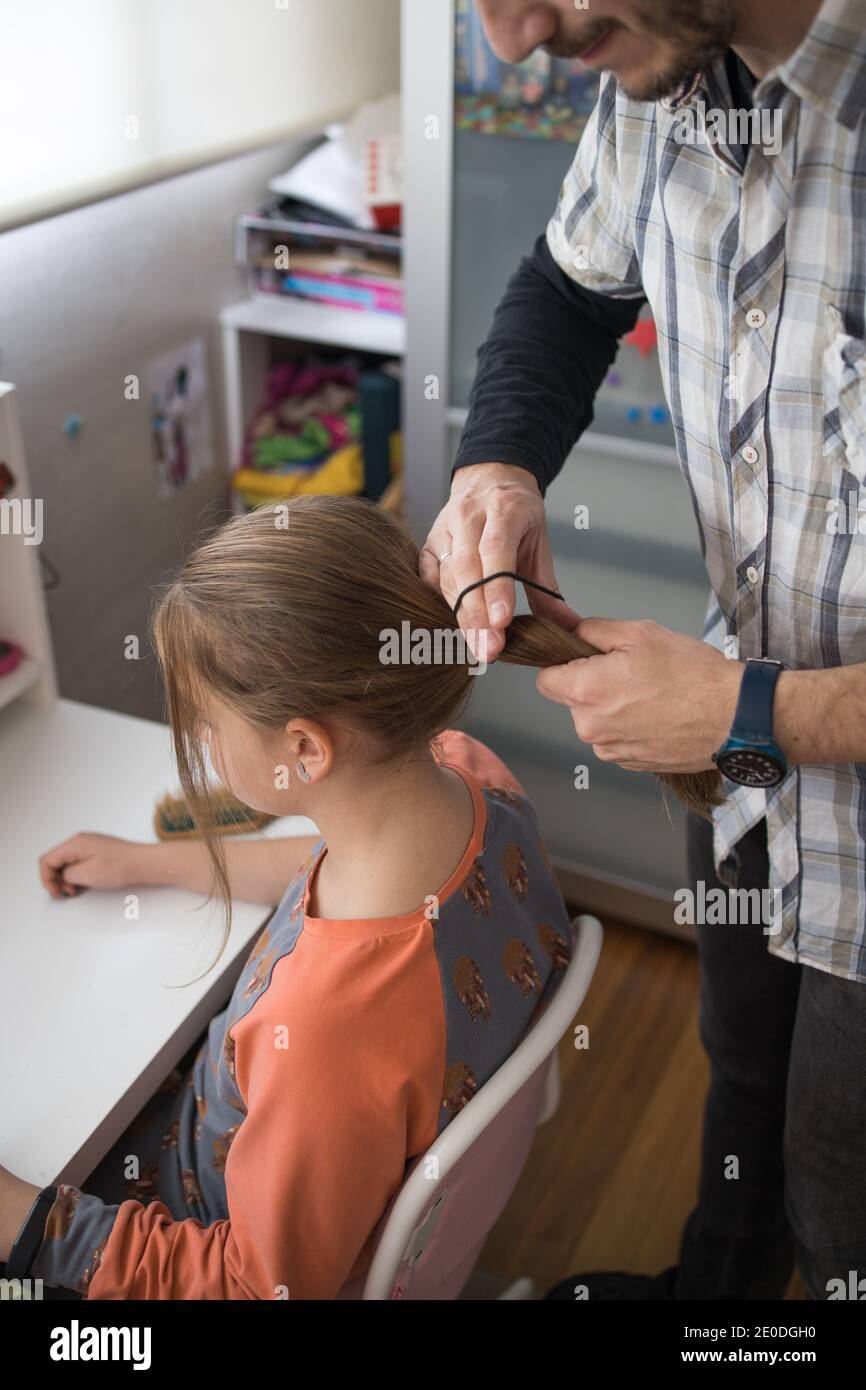 Side view of crop unrecognizable single dad doing ponytail for daughter ...