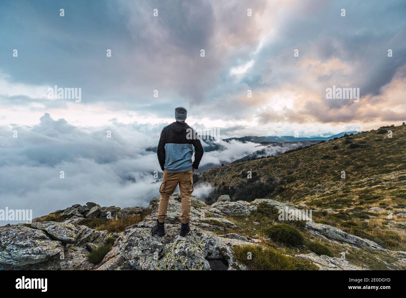 Back view of male hiker standing on top of hill and enjoying freedom in ...