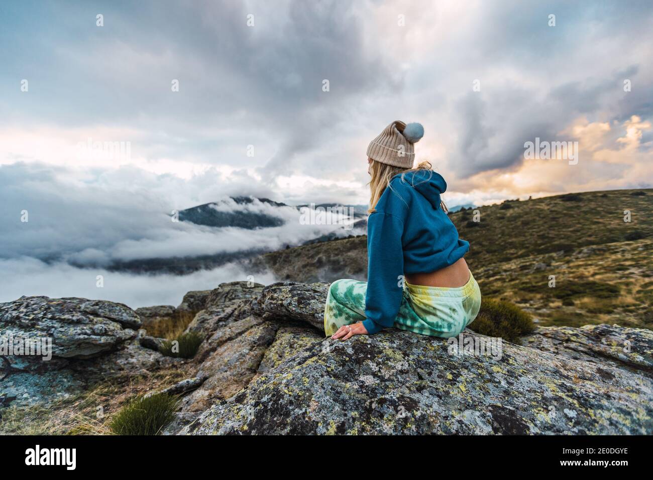 Side view of female explorer sitting on rock enjoying nature and ...