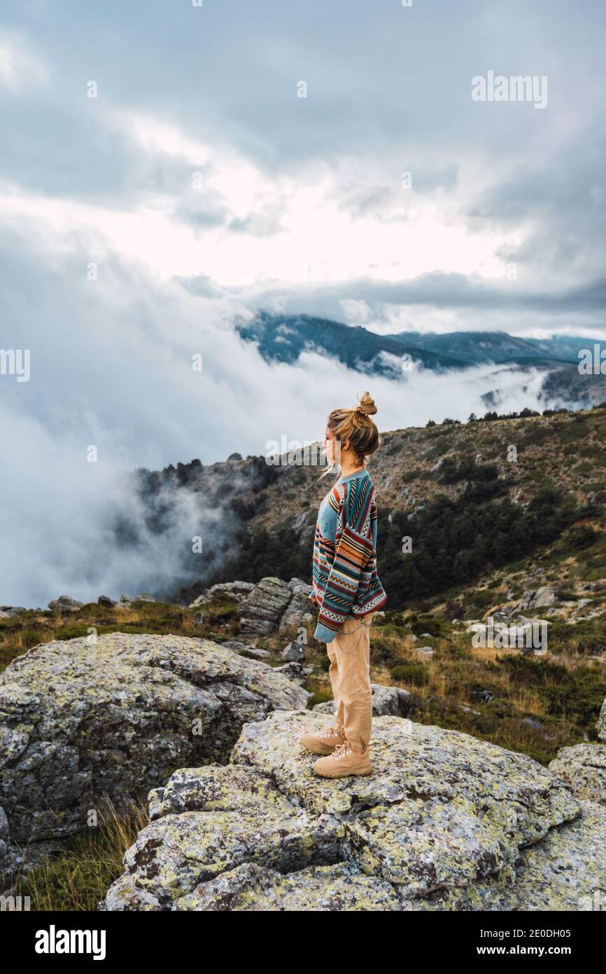 Side view of female explorer standing on rock enjoying nature and ...